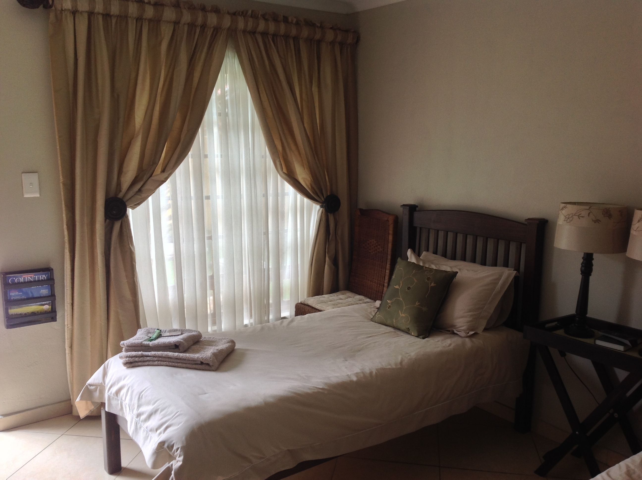 Quarto de hotel com cama, cortinas, abajur e placa na parede.
