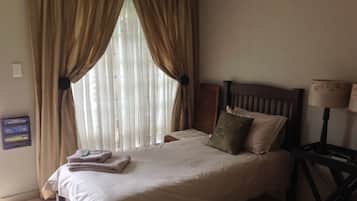 Quarto de hotel com cama, cortinas, abajur e placa na parede.