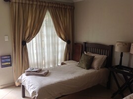 Quarto de hotel com cama, cortinas, abajur e placa na parede.
