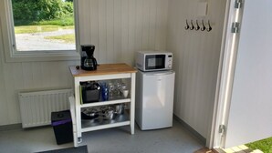 Uma cozinha compacta equipada com micro-ondas, cafeteira e prateleiras de armazenamento.