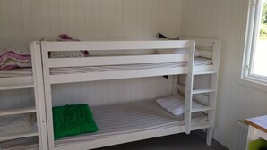 Quarto com beliche, janela e manta verde na cama inferior.