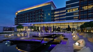 Um hotel moderno com área de piscina, espaço ao ar livre para sentar e uma entrada bem iluminada.