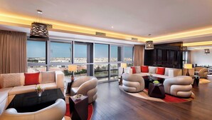 Uma sala de estar moderna com um conjunto de sofás, uma mesa de centro e vista para a cidade.