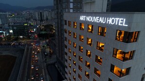 Um hotel moderno com uma placa grande, vários andares e uma rua movimentada ao fundo.