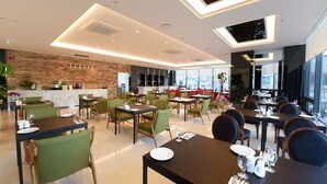 Um restaurante moderno com várias áreas de refeição, incluindo um bar e um espaço com vista para a cidade.