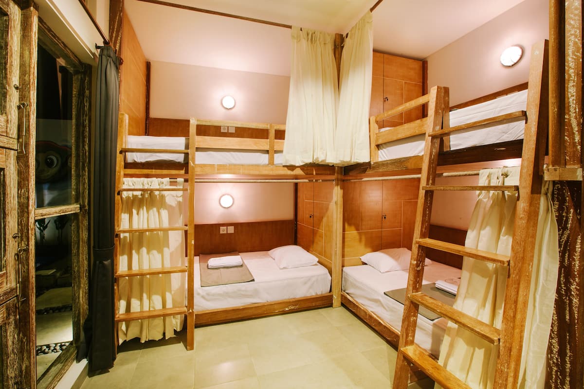 Um quarto com beliches, paredes de madeira e cortina.