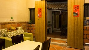 Interior de restaurante japonês tradicional com portas de correr de madeira, um sofá acolchoado verde e uma mesa com cadeiras.