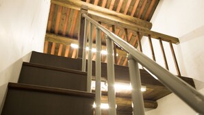 Uma escada de madeira com grades de metal e uma parede branca.