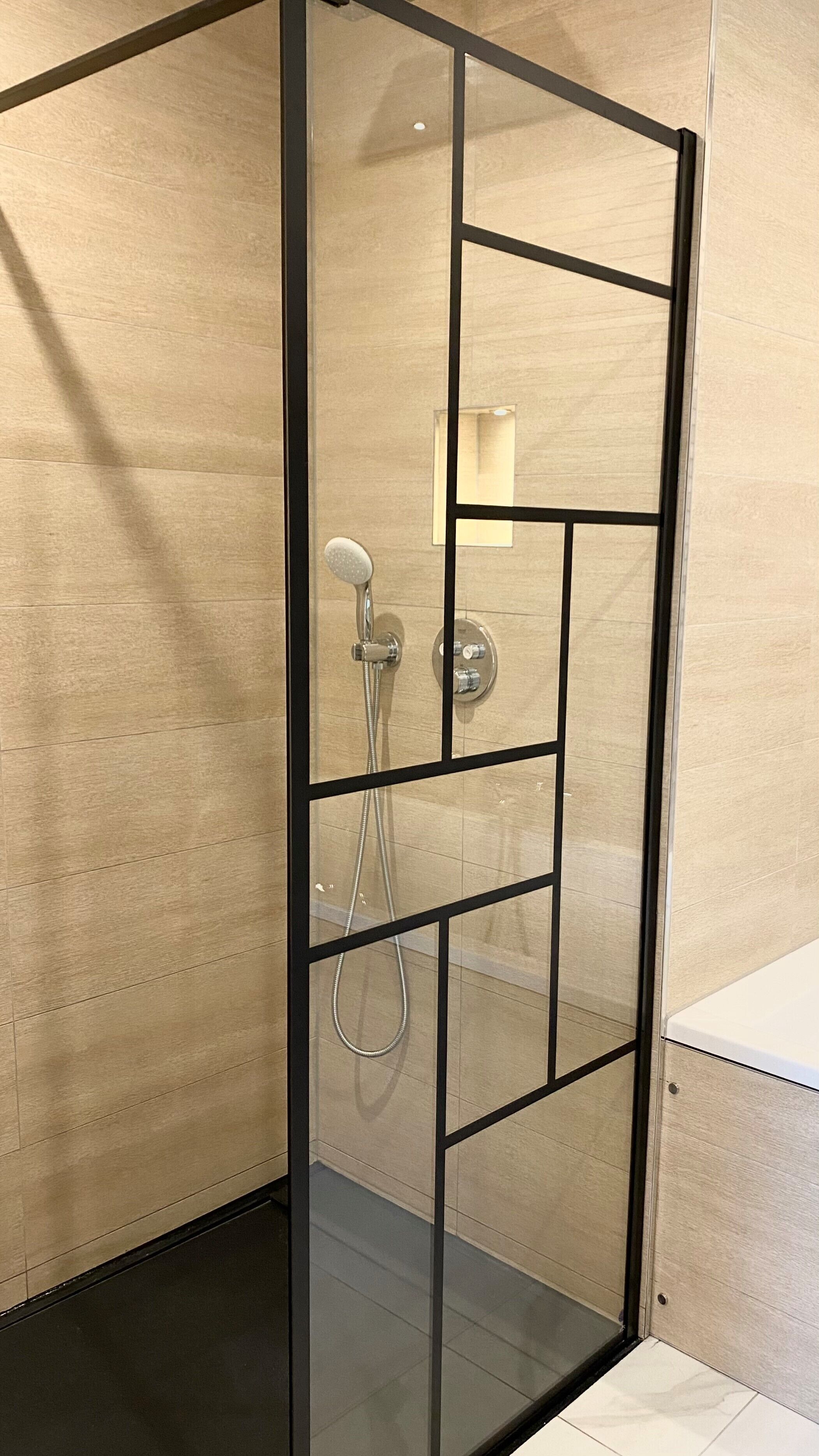 Um box de chuveiro moderno com porta de vidro e moldura preta.