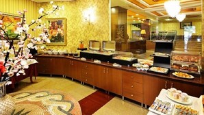 Uma área de buffet com diversos tipos de comida, um vaso decorativo com flores e um piso estampado.