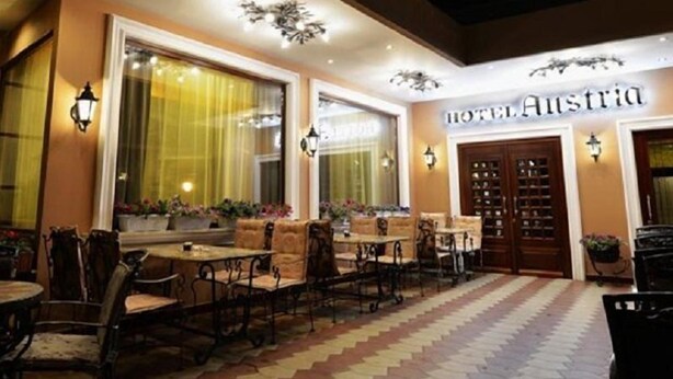 Um saguão de hotel com uma entrada ampla, várias áreas de estar e uma placa com a inscrição 'HOTEL AUSTRIA'.