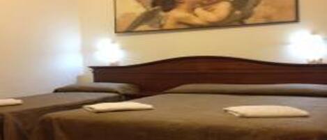 Quarto de hotel com duas camas de solteiro, cada uma com uma almofada e uma toalha dobrada.