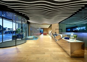Um hall moderno com uma recepção de design curvo, paredes de vidro e piso de madeira.