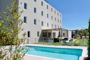 Um edifício moderno com piscina, área de estar externa e gramado bem cuidado.