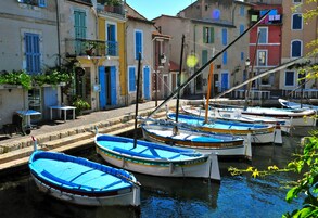 Barcos atracados em uma via navegável estreita, entre edifícios.