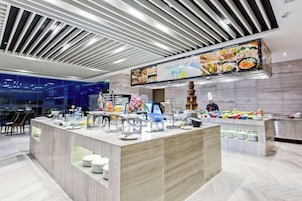 Uma moderna disposição de buffet com tela digital de menu, estações de autoatendimento e diversas opções de comida.