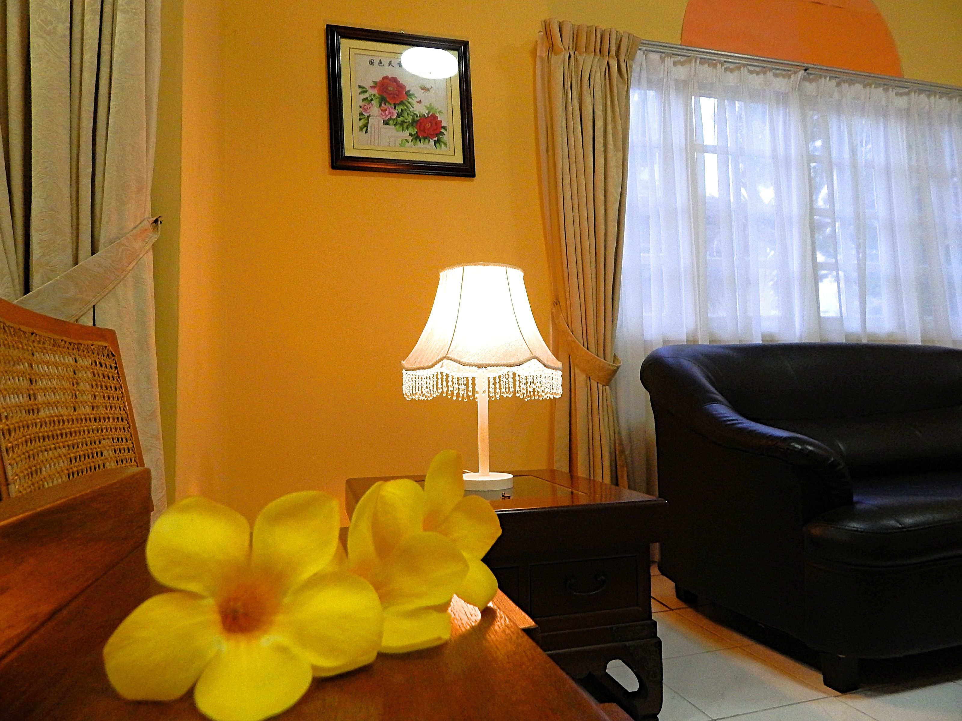Quarto com uma mesa de madeira, um sofá preto, uma luminária e um quadro na parede.