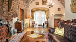 Uma sala de estar aconchegante com uma parede de pedra, um sofá de couro, uma mesa de centro de madeira e um tapete estampado.