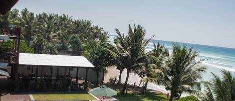 Área da piscina com vista para a praia e o oceano.