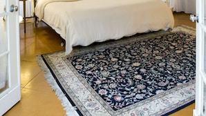 Quarto com uma cama grande, mesa de cabeceira, abajur e vista para uma varanda.