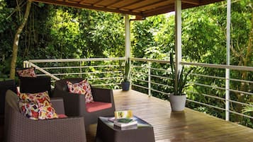 Um deck externo com móveis de vime e um vaso de planta.