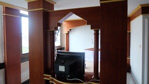 Um corredor com colunas de madeira e uma televisão no centro.