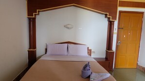 Uma cama de solteiro com cabeceira de madeira, uma mesa de cabeceira e uma porta em um quarto com piso de azulejos.