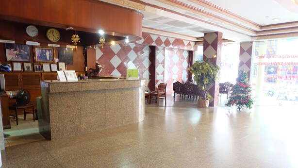 Uma área de recepção de hotel com balcão de mármore, mobiliário de madeira e um pinheiro de Natal.