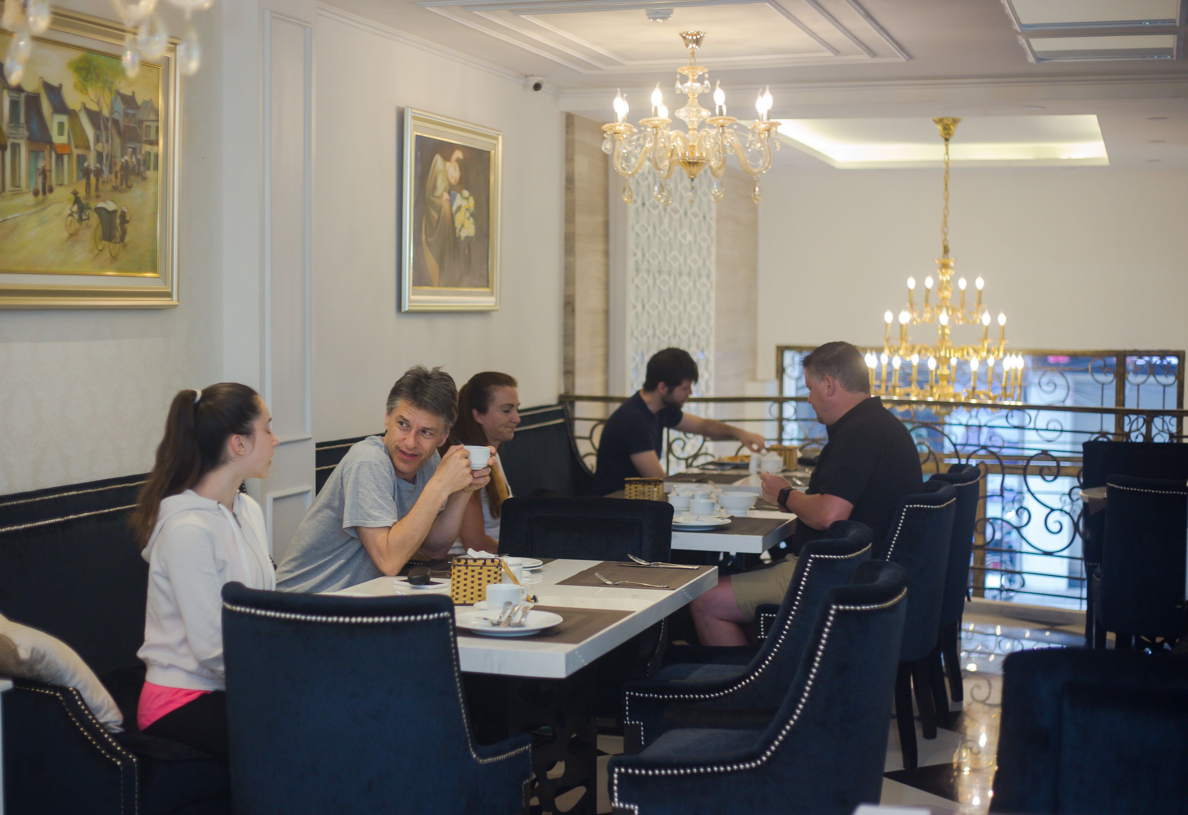 Uma sala de jantar com mesas e cadeiras, um candelabro e obras de arte emolduradas nas paredes.
