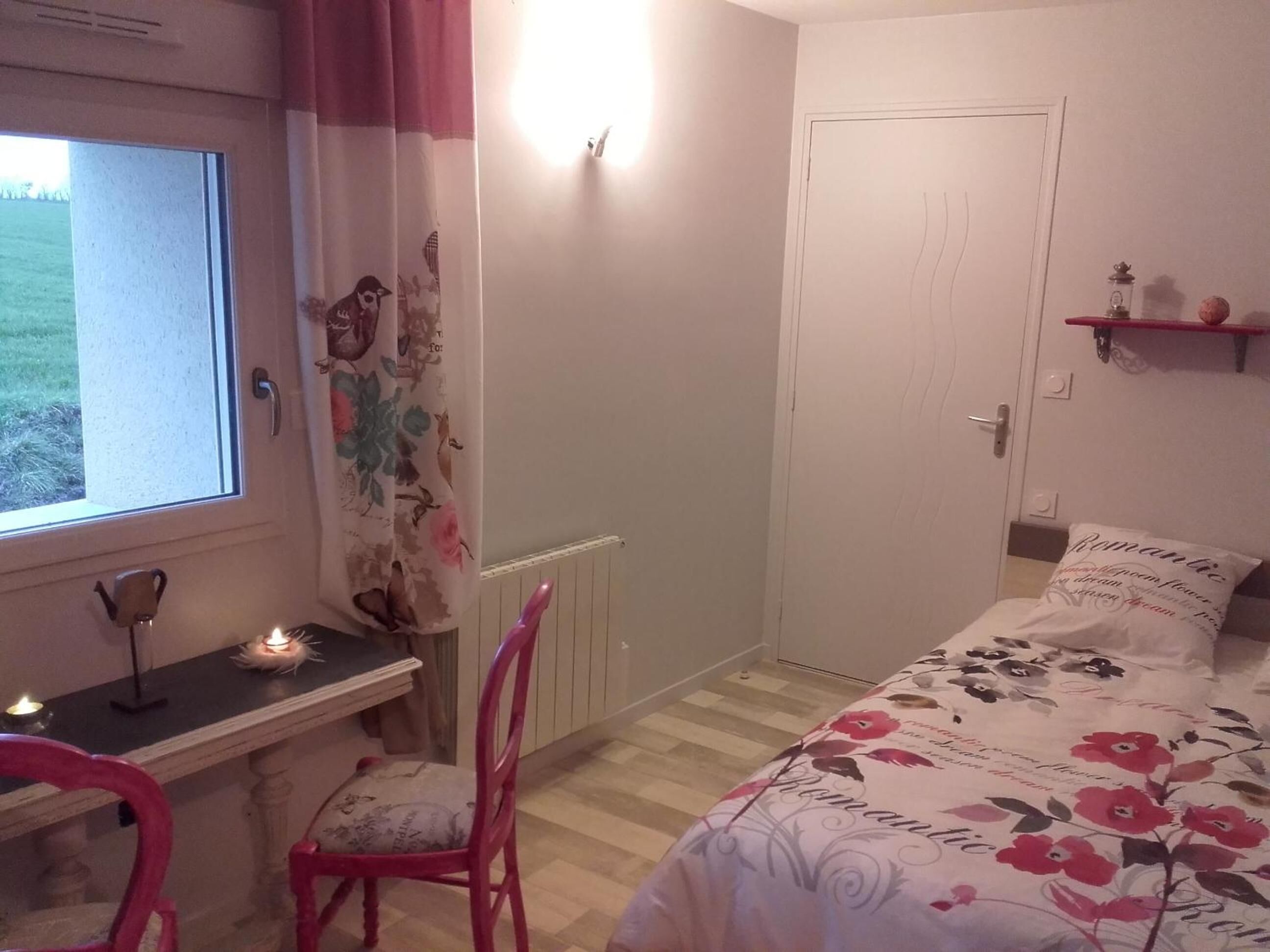 Quarto com cama, escrivaninha, cadeira, janela com cortinas e porta.