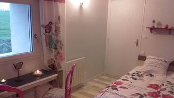 Quarto com cama, escrivaninha, cadeira, janela com cortinas e porta.