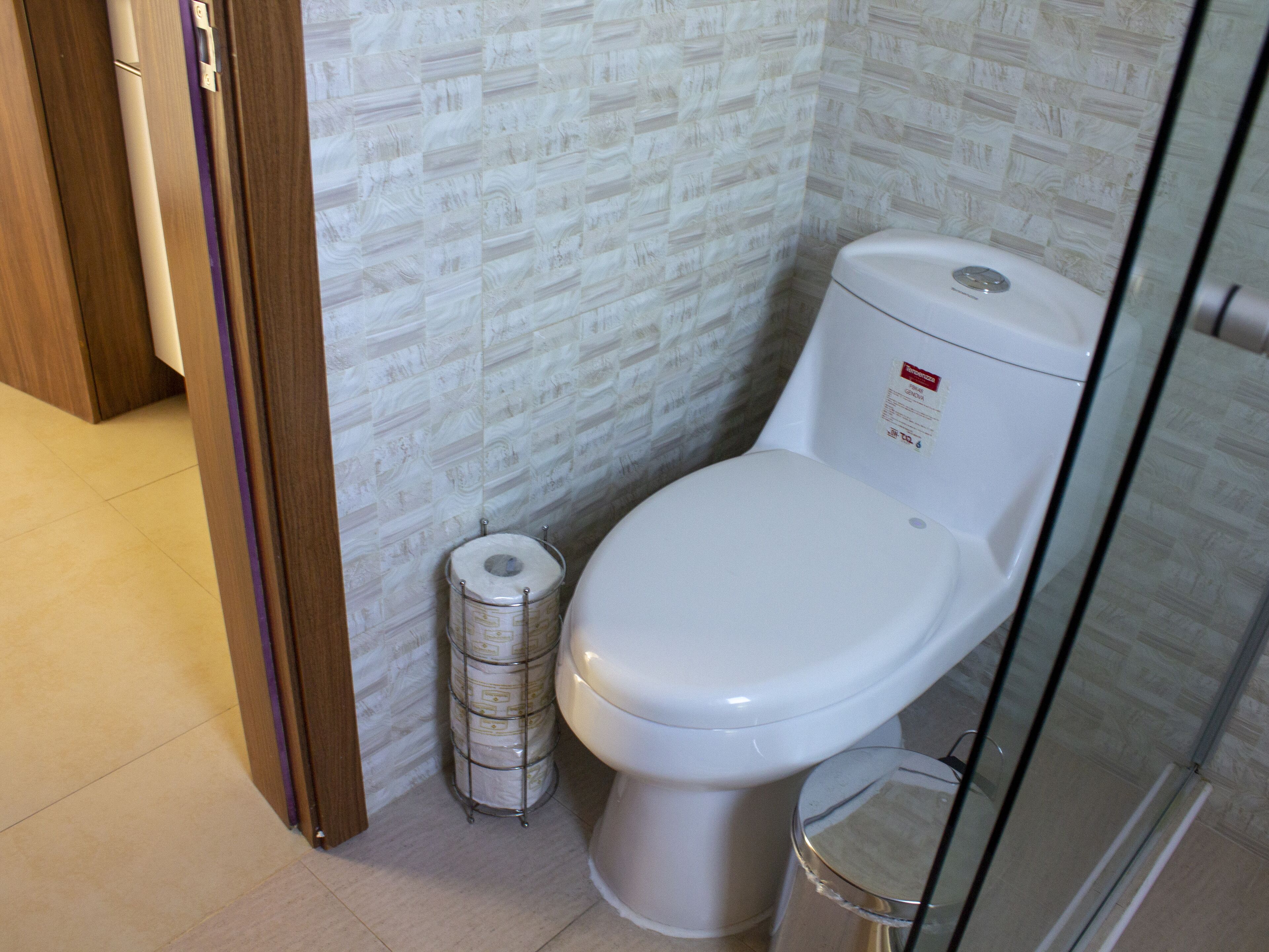 Casa de banho com sanita, dispensador de papel e lixeira.