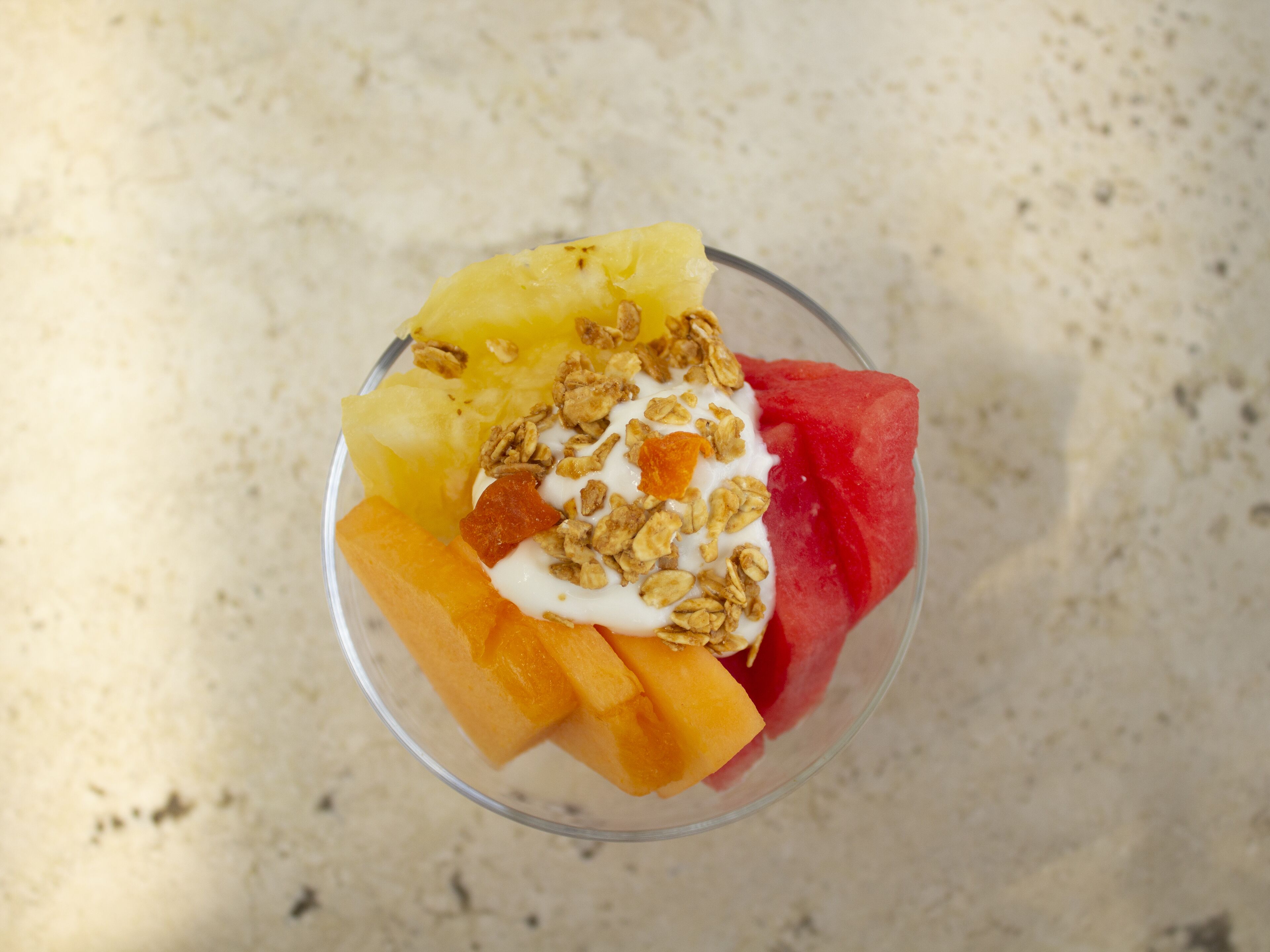 Uma tigela de salada de frutas com iogurte e granola.