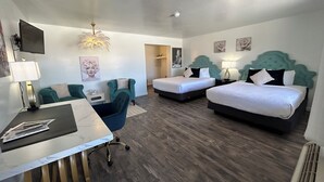 Quarto de hotel com duas camas, uma escrivaninha, uma cadeira e uma televisão.