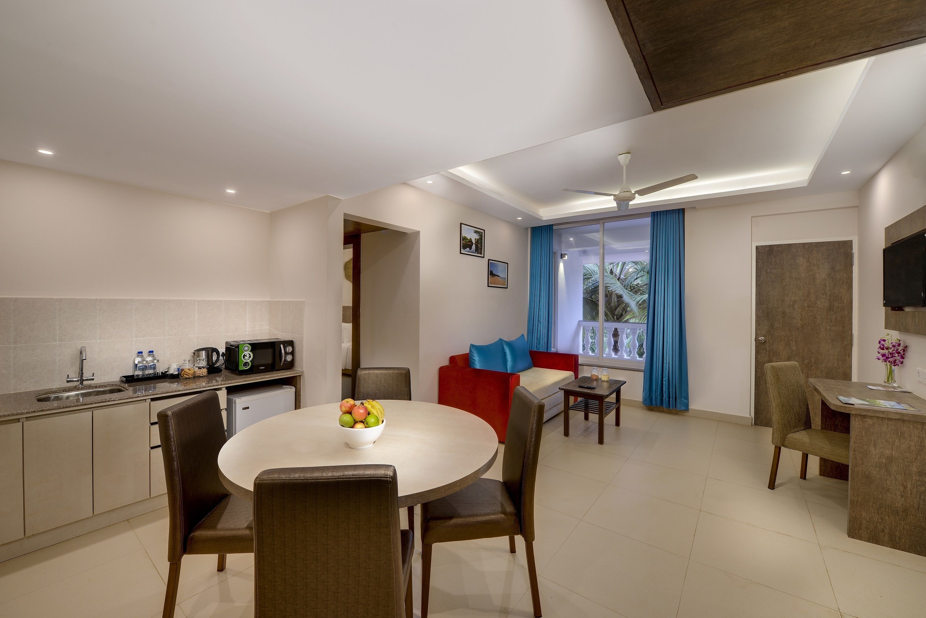 Cozinha moderna com área de jantar, sofá vermelho e vista para o exterior.