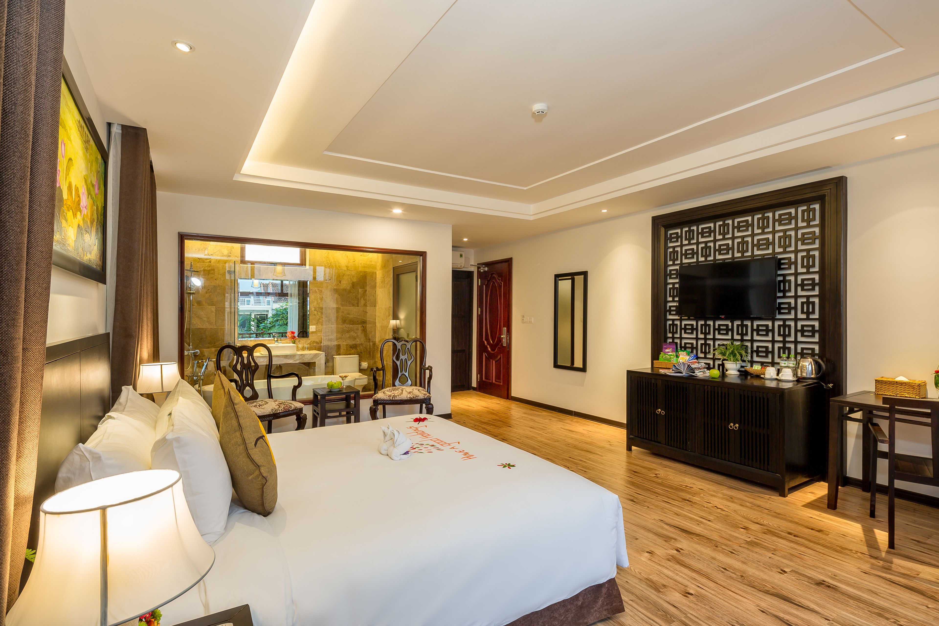 Quarto de hotel moderno com uma cama grande, uma escrivaninha e uma televisão.