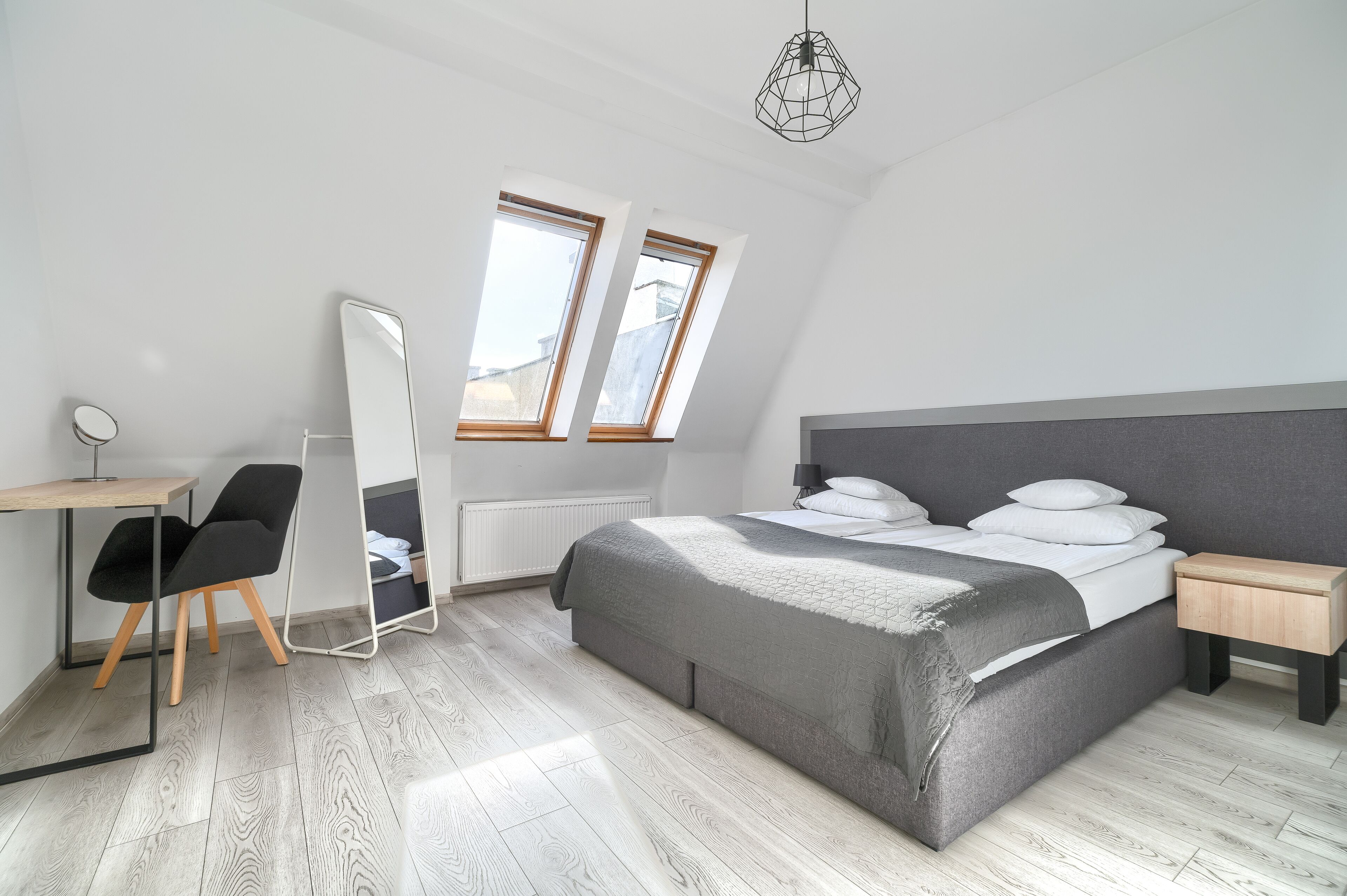 Quarto moderno com uma cama grande, uma escrivaninha, uma cadeira e um guarda-roupa.