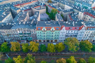 Vista aérea de uma área urbana densamente povoada com edifícios altos, uma linha de trem e árvores.