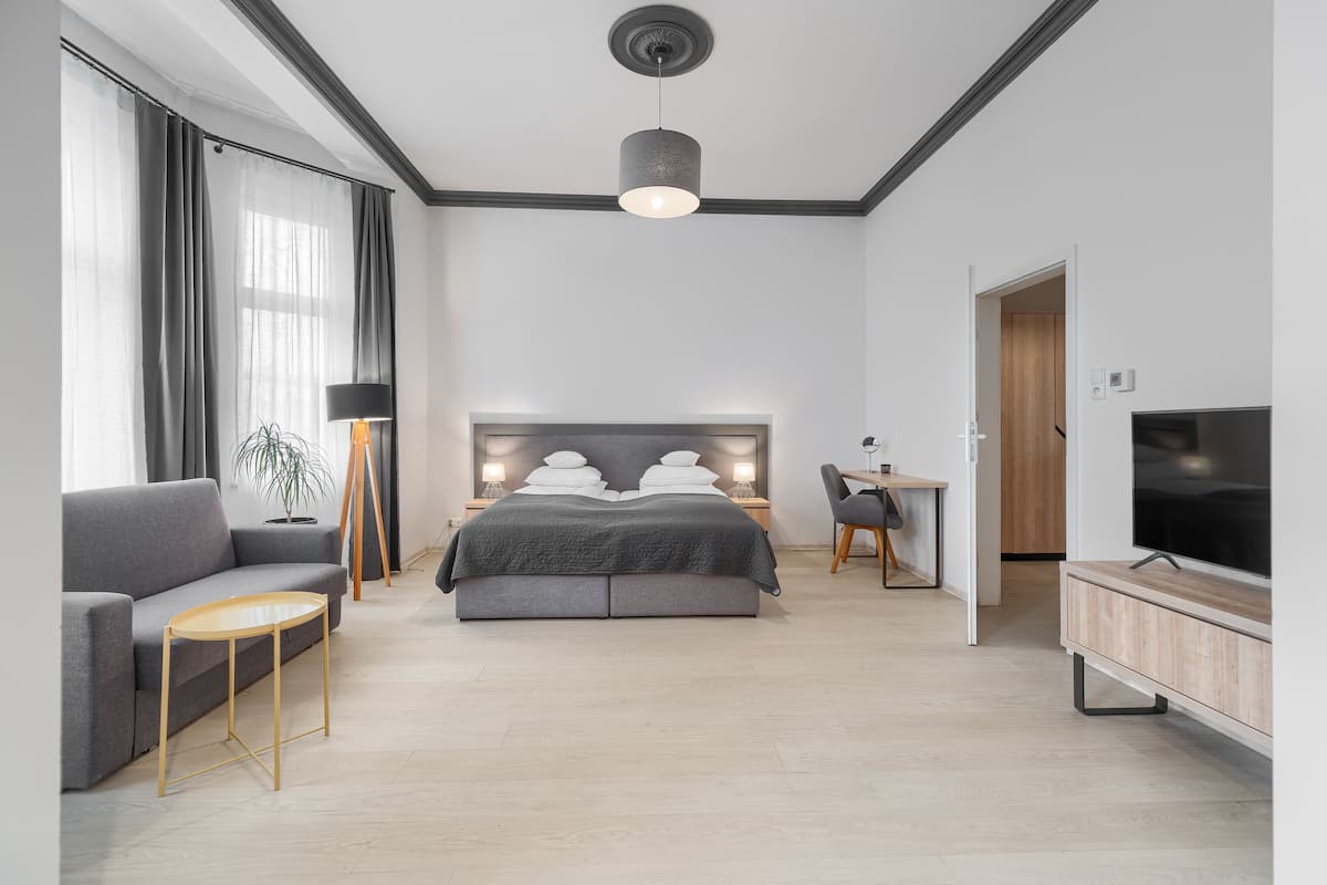 Quarto moderno com cama, sofá, escrivaninha e televisão.