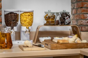 Buffet de café da manhã com diversos alimentos e acompanhamentos.