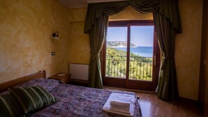 Quarto com cama, mesa de cabeceira e janela com cortinas.