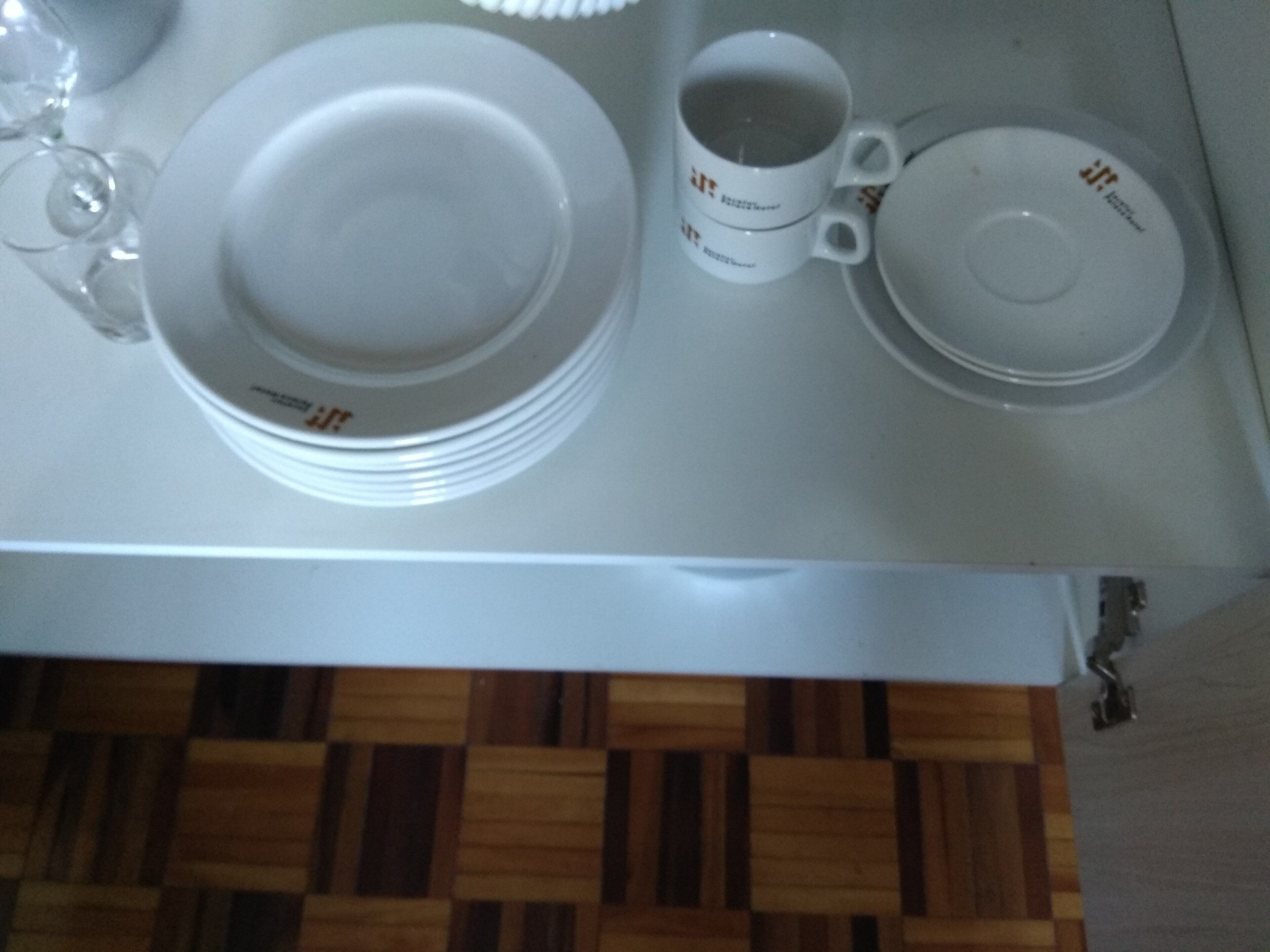 Uma cozinha com pratos, caneca e tigela brancos em cima do balcão.