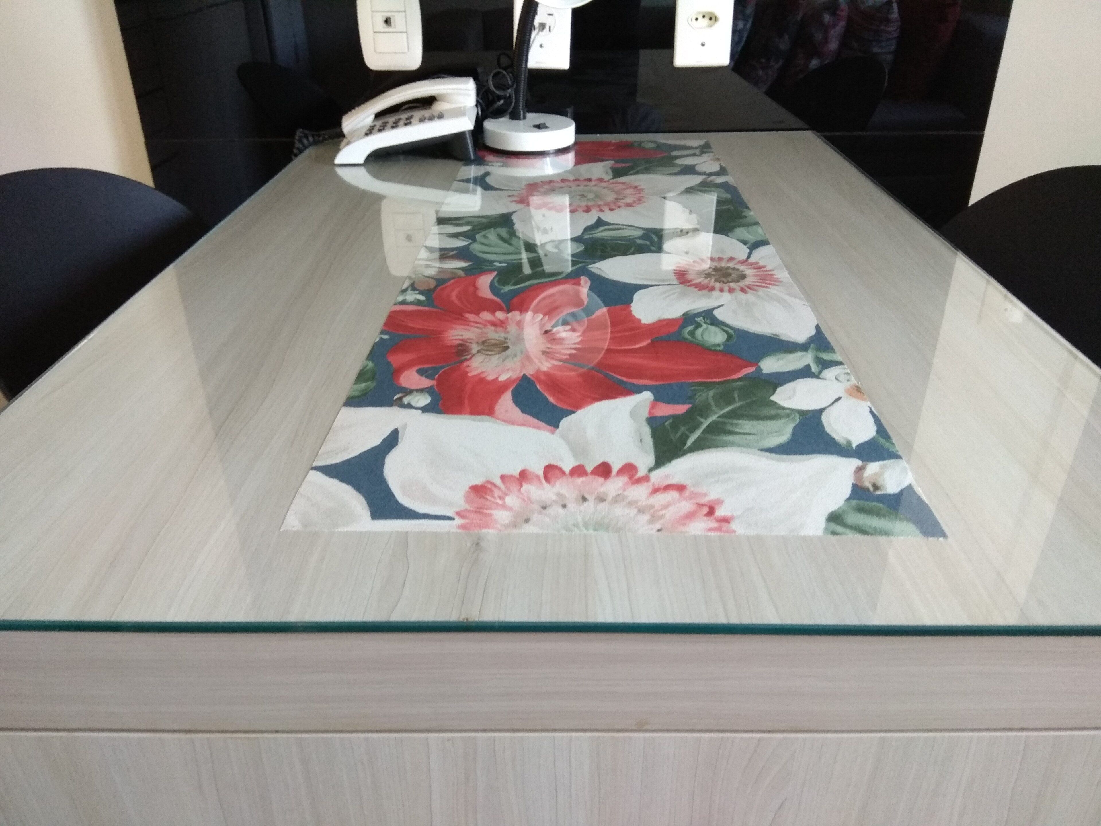 Uma mesa de conferência com toalha de mesa florida, um telefone e um filtro de linha.