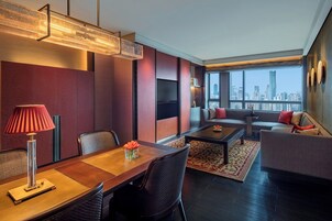 Quarto de hotel moderno com área de refeições, sofá e vista para a cidade.