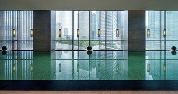 Um interior moderno com grandes janelas, piso refletivo e luminárias fixadas na parede.