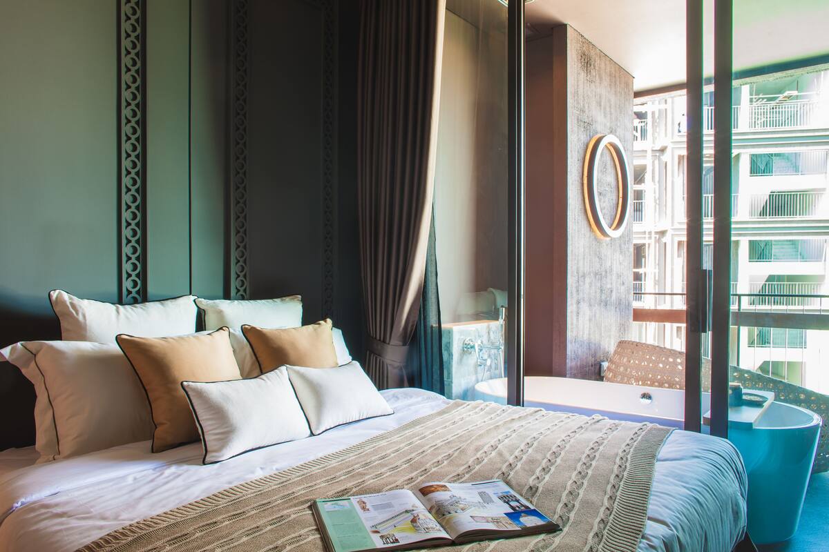 Quarto de hotel com uma cama grande, vista do exterior do edifício e uma janela com cortina.