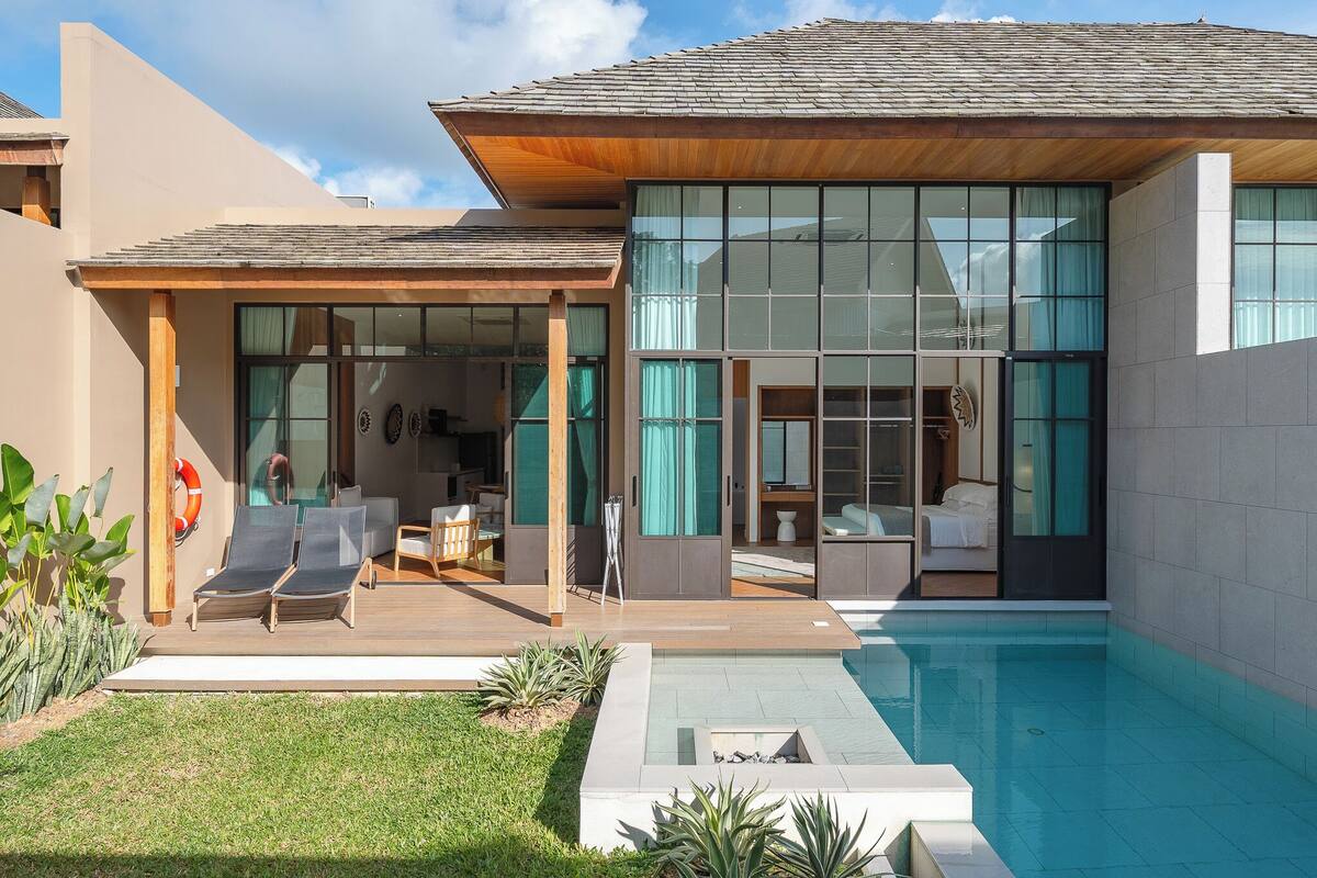 Uma casa moderna com piscina, varanda coberta e uma grande porta de vidro que dá para uma sala de estar.