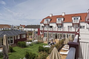 Hotel com um pátio que oferece áreas de estar ao ar livre, piscina e telhado de telhas vermelhas.