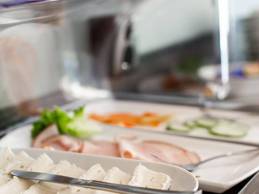 Buffet com diversos alimentos, incluindo carnes fatiadas e legumes.