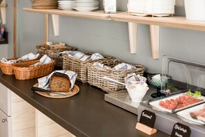 Disposição de buffet com diversos alimentos, cestas e uma placa que indica 'Salami'.